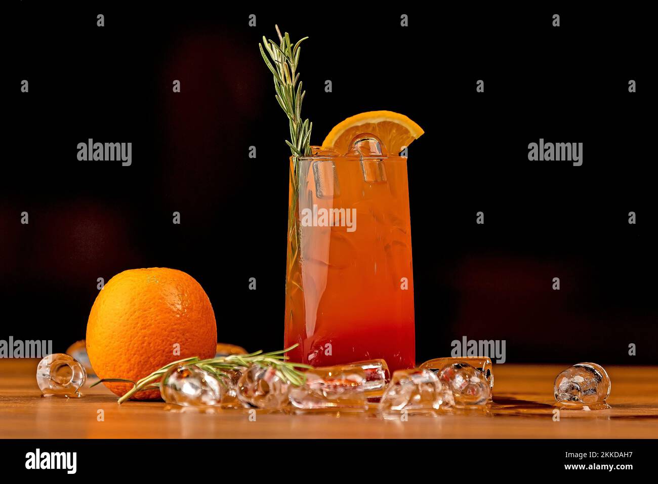 A glass of cold delicious orange juice, ice cubes, and an orange on a ...