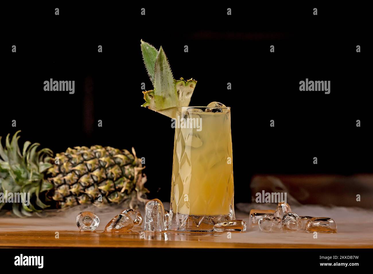 A glass of cold delicious pineapple juice, ice cubes, and a whole ...