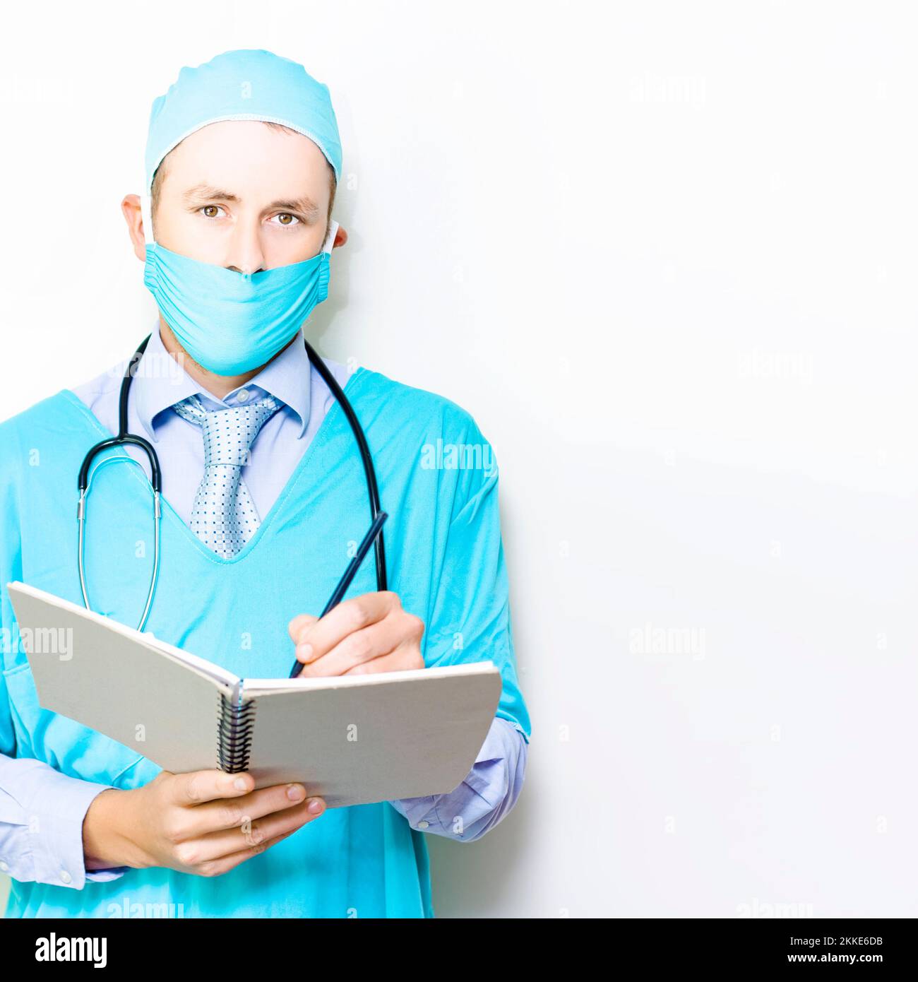 Doctor or surgical nurse in gown and mask standing writing in a spiral ...