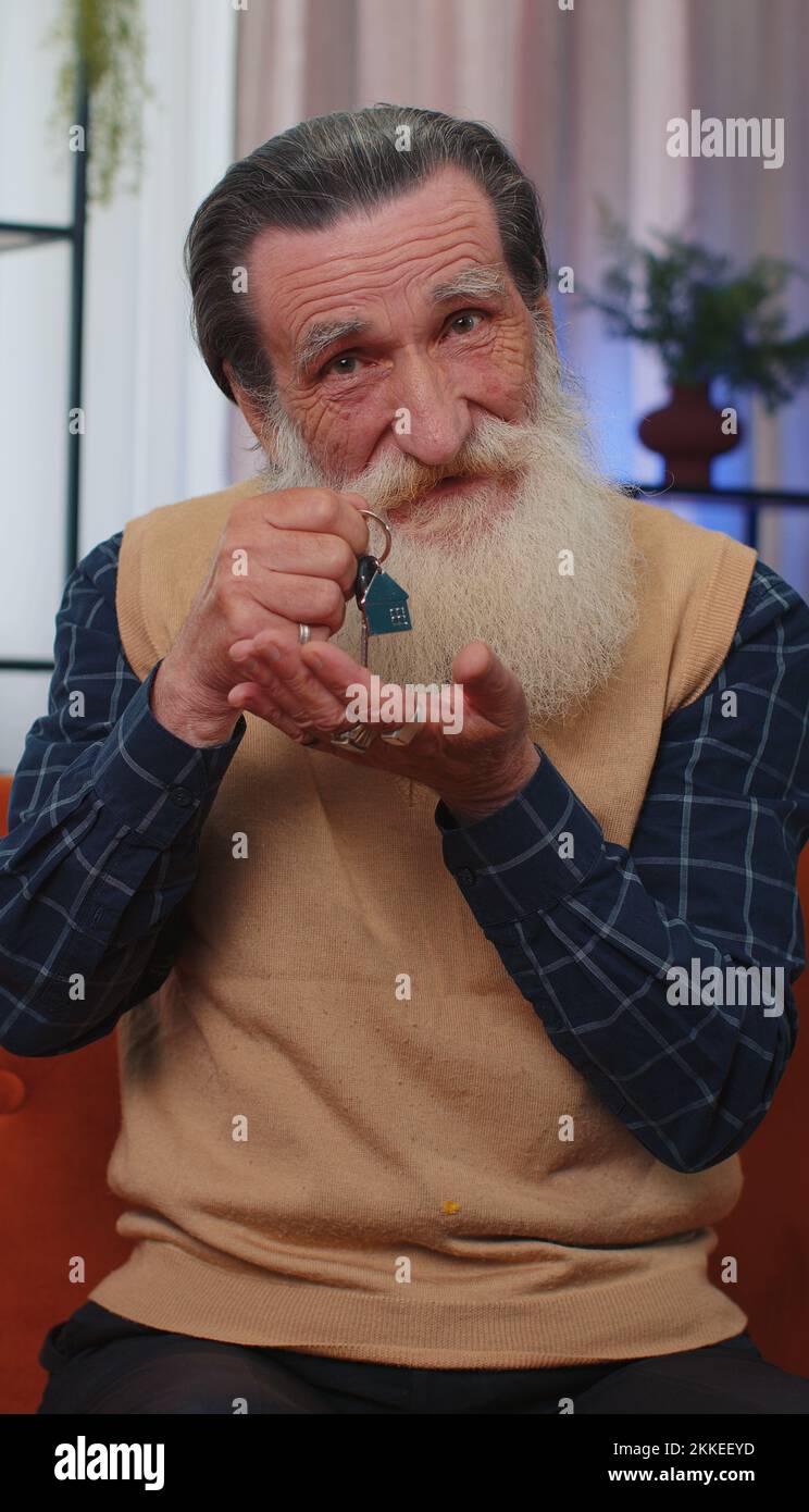 Senior old grandfather real estate agent lifting hand showing the keys ...