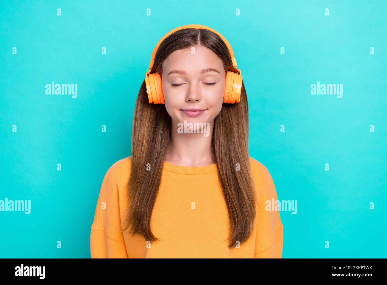 Photo of young funny dreamy girl wear orange wireless earbuds closed ...