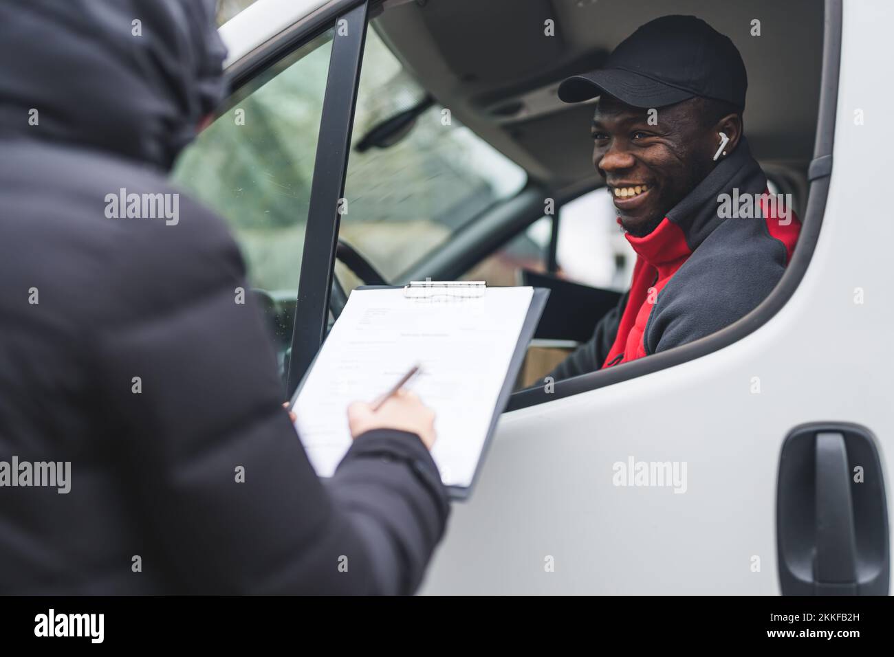 Young adult black man sitting inside white van looking out the window ...