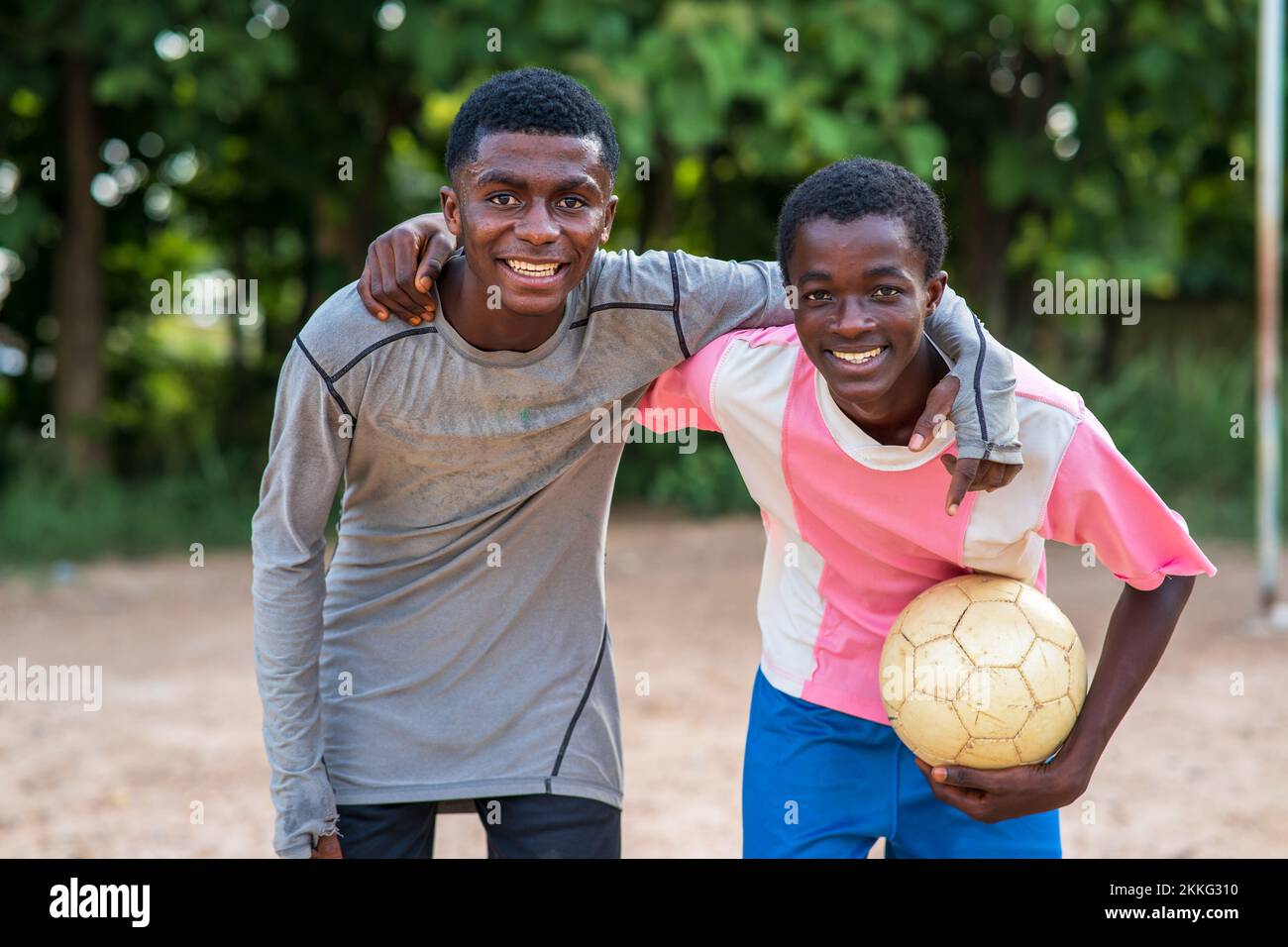 Two young African boys smiling happily at the camera with arms around ...