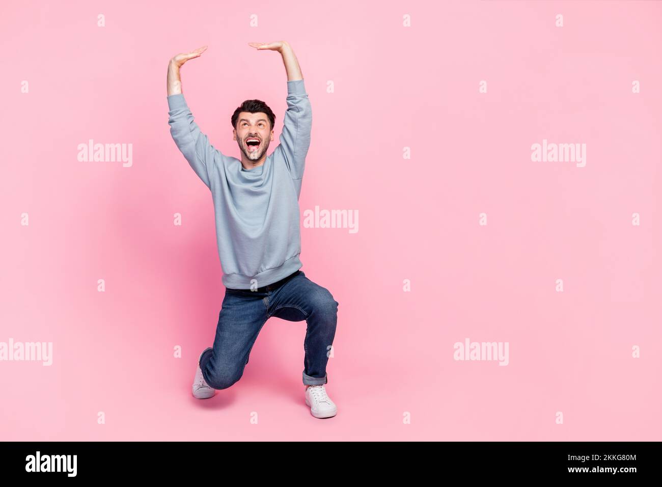 Full size photo of handsome young guy raise hands hold look heavy empty ...