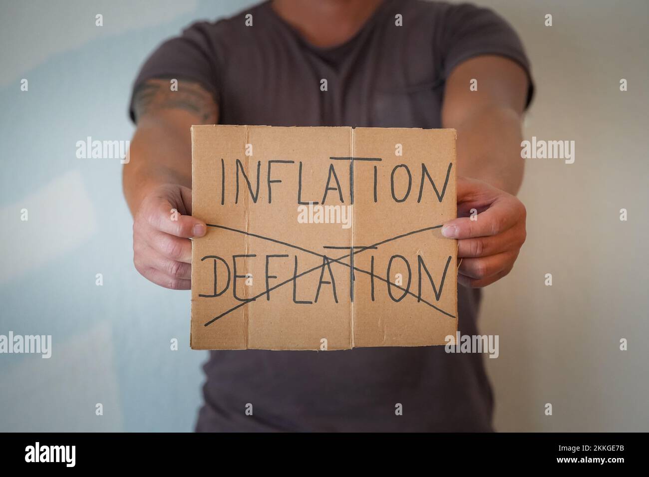 A person holding a cardboard sign with the word inflation and the word ...