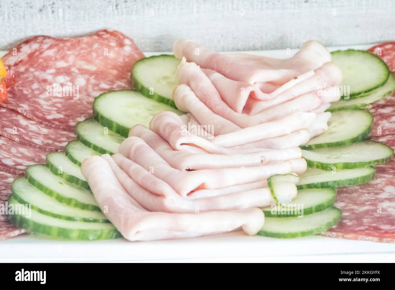 A closeup of ham and cucumber slices on a white plate in a buffet Stock ...