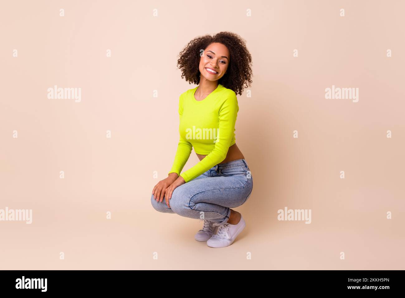 Full body photo of cute young lady curly hair squat crouch beaming ...