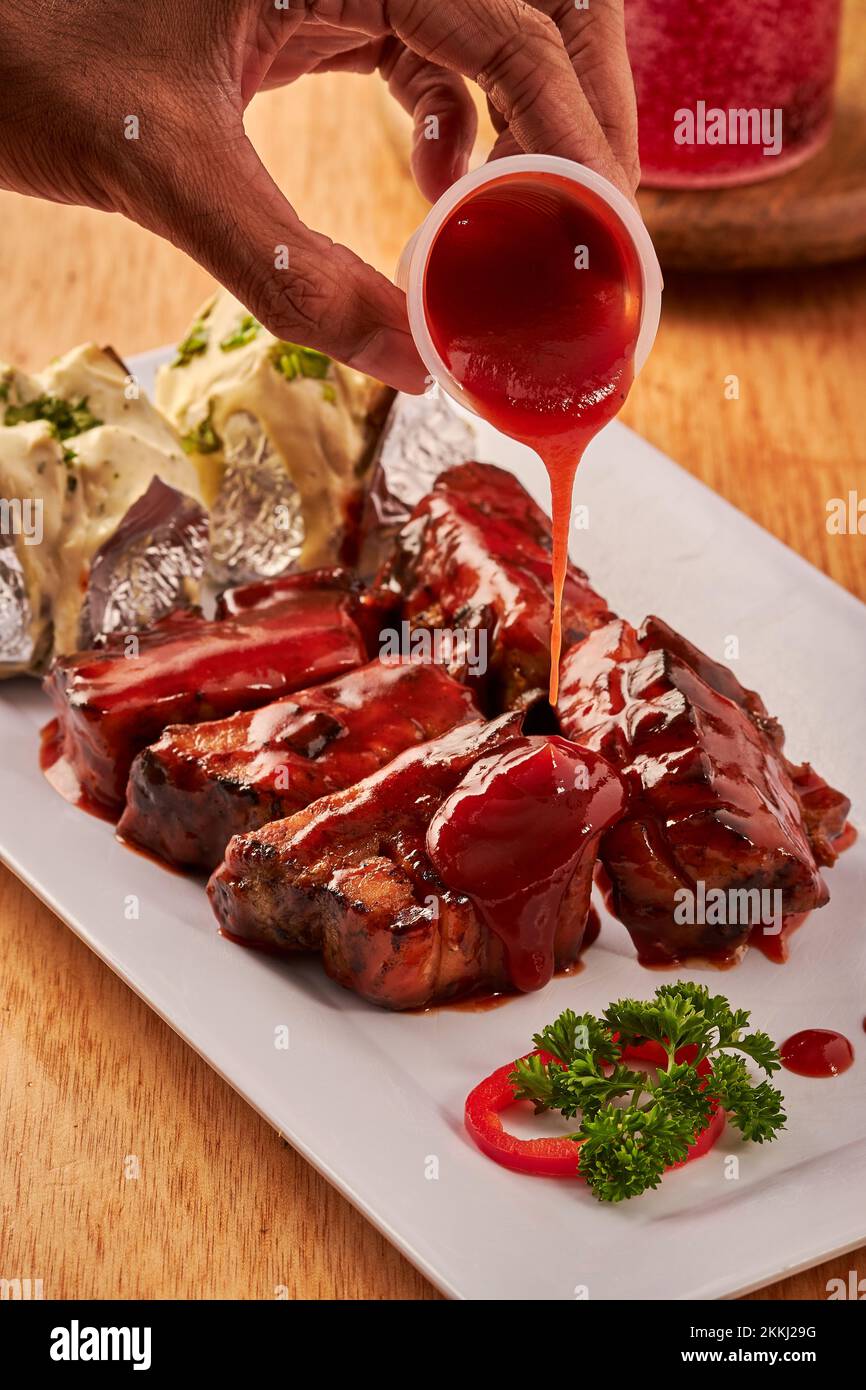 A vertical shot of a male hand pouring ketchup on a sliced steak Stock ...