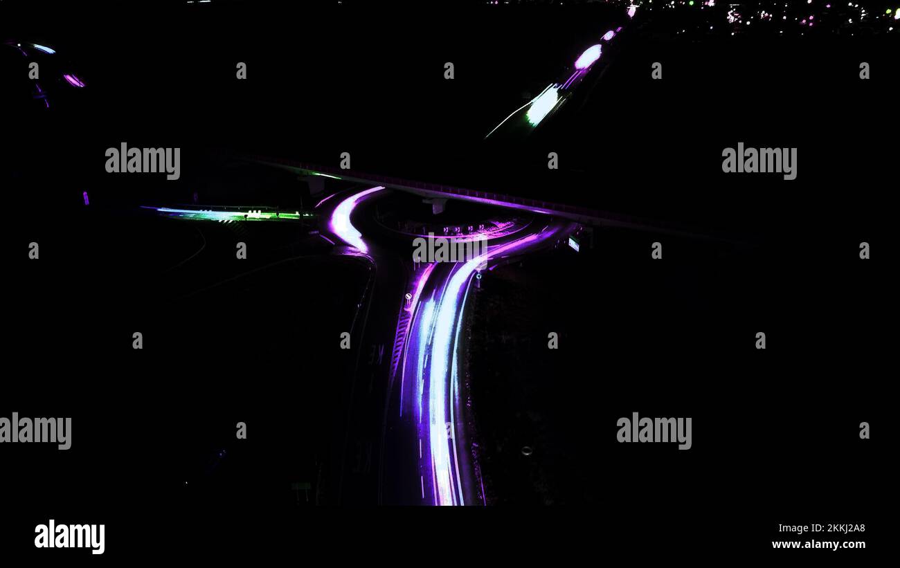 An aerial view of a roundabout road at night with long exposure neon ...