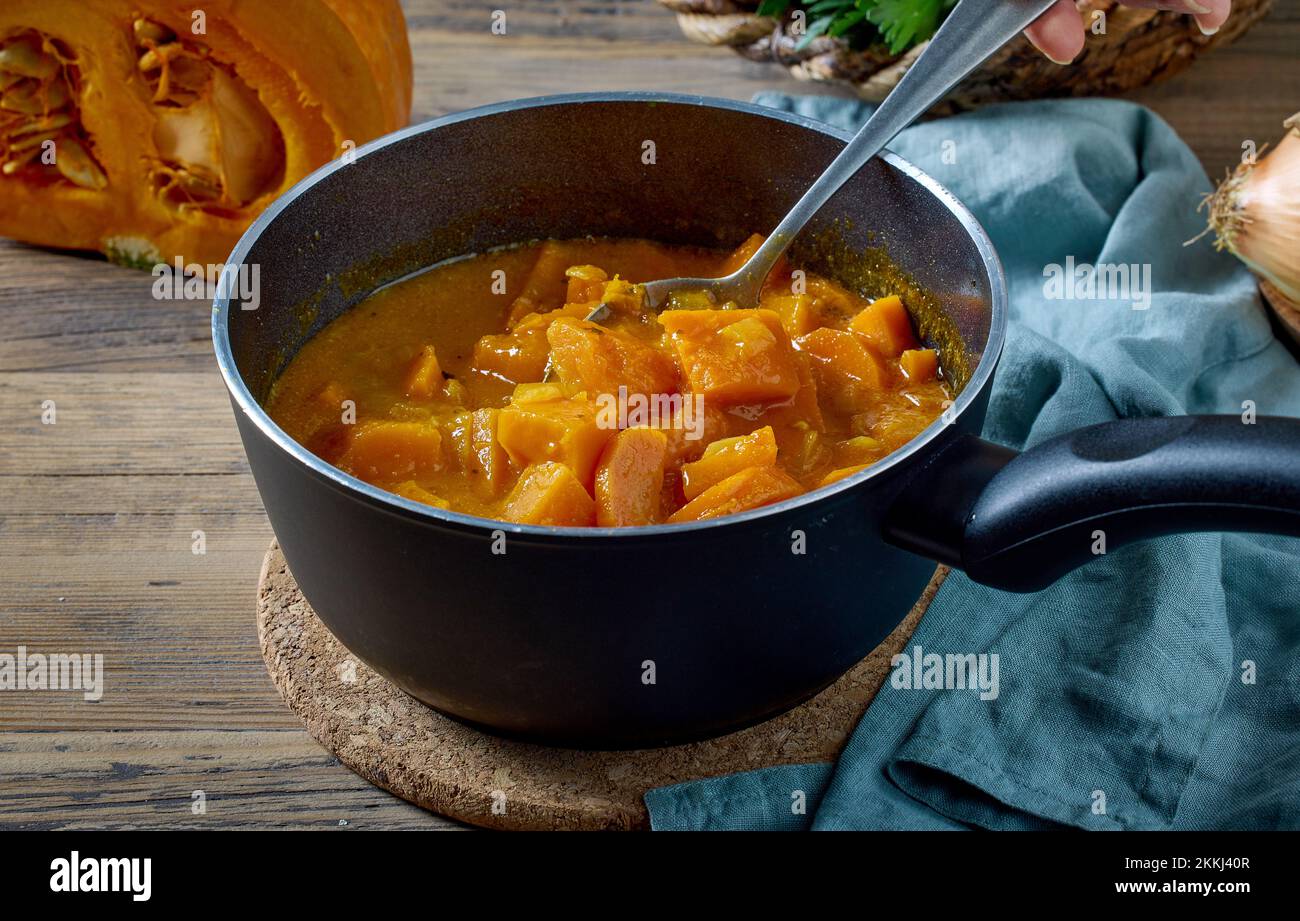 pumpkin and carrot stew in a cooking pot on rustic kitchen table ...
