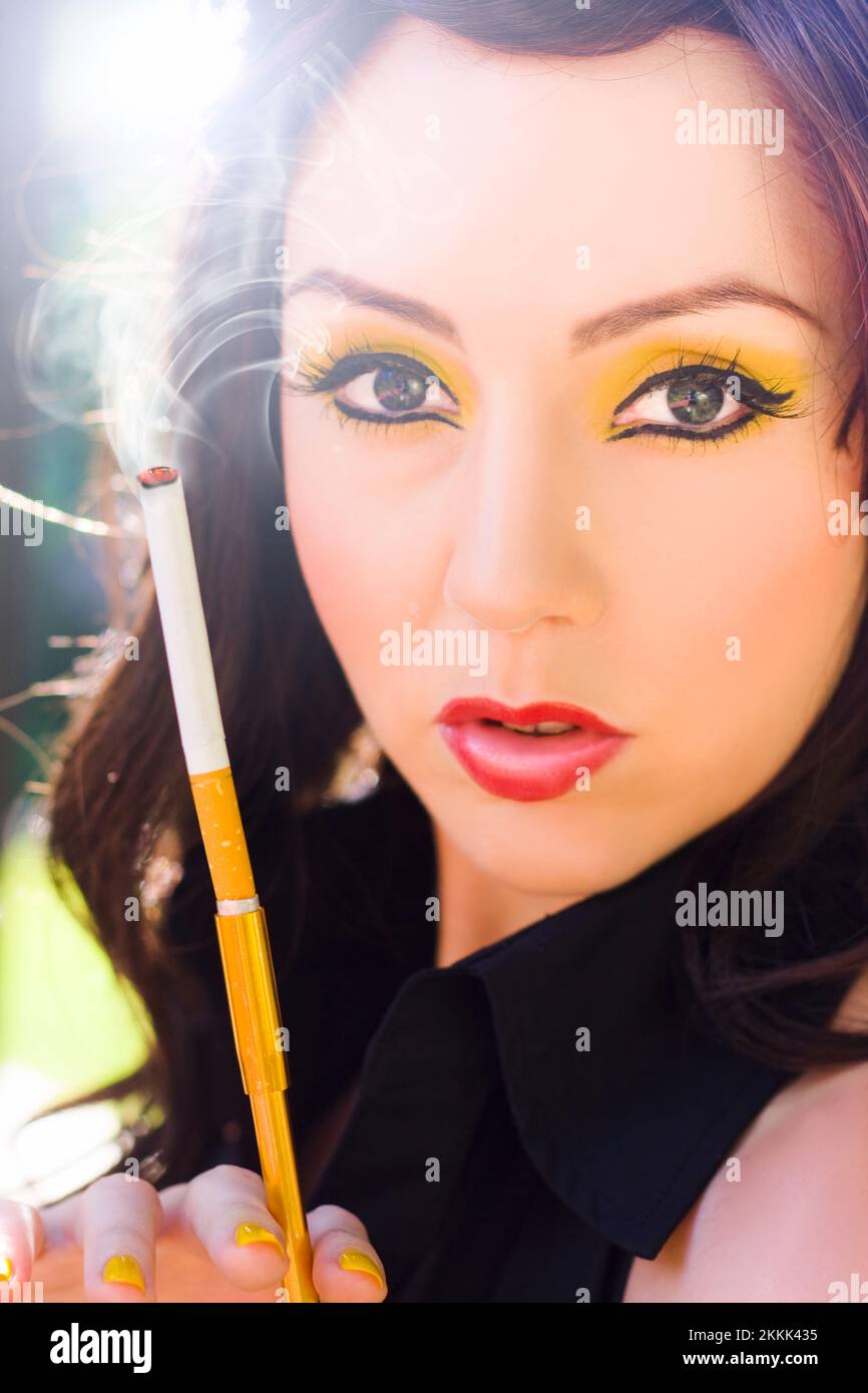 Intense Refined And Poised Vintage Woman Holding Up A Retro Cigarette Holder Outdoors In The