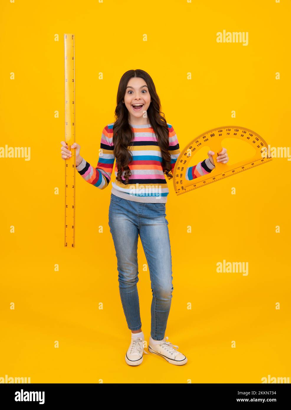 Back to school. School girl hold ruler measuring isolated on yellow ...