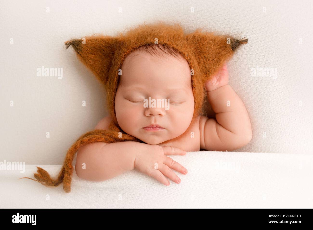 A newborn girl in the first days of life in a brown tiger cap with cute ...