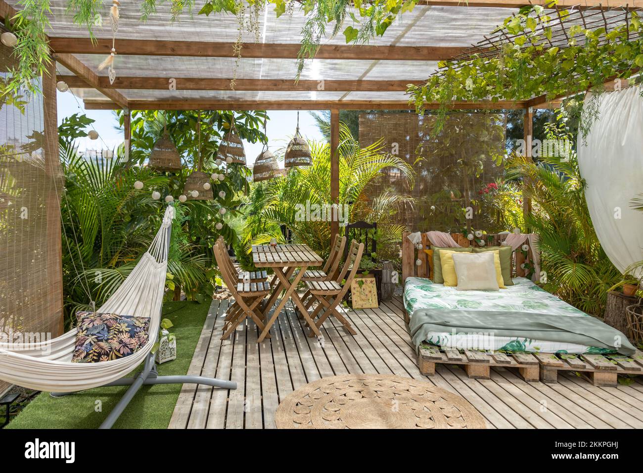A beach gazebo interior with a hammock, bed and wooden table with ...