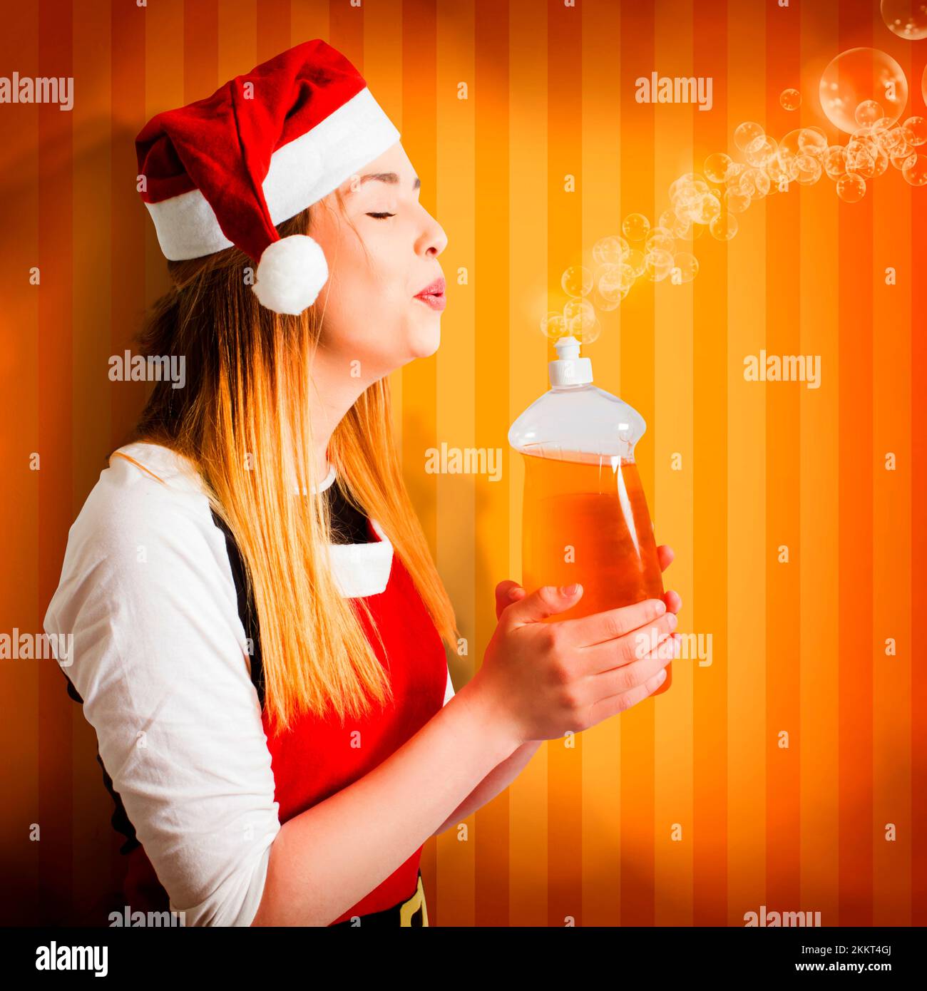 Funny seasonal portrait of a beautiful christmas helper girl blowing on ...