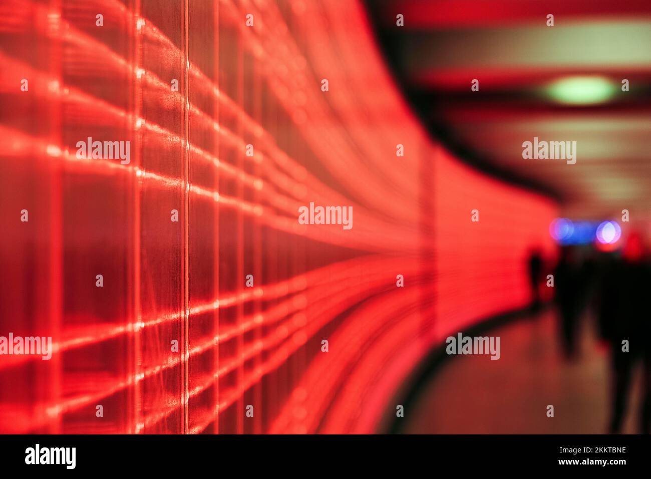 Passers-by in underground passage Passerelle, red illuminated wall ...