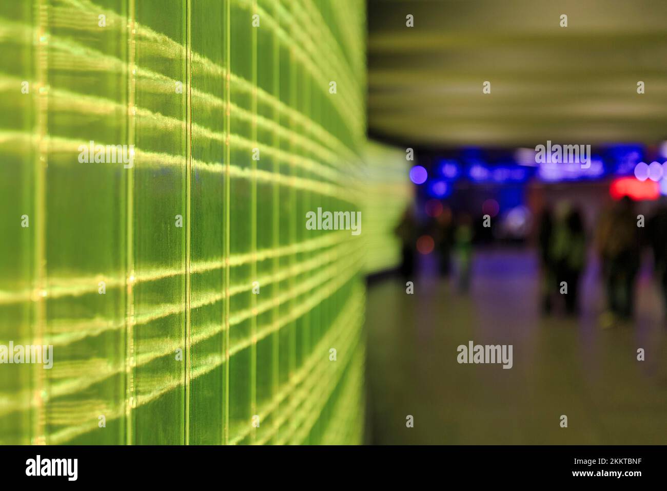 Passers-by in underground passage Passerelle, yellow illuminated wall ...