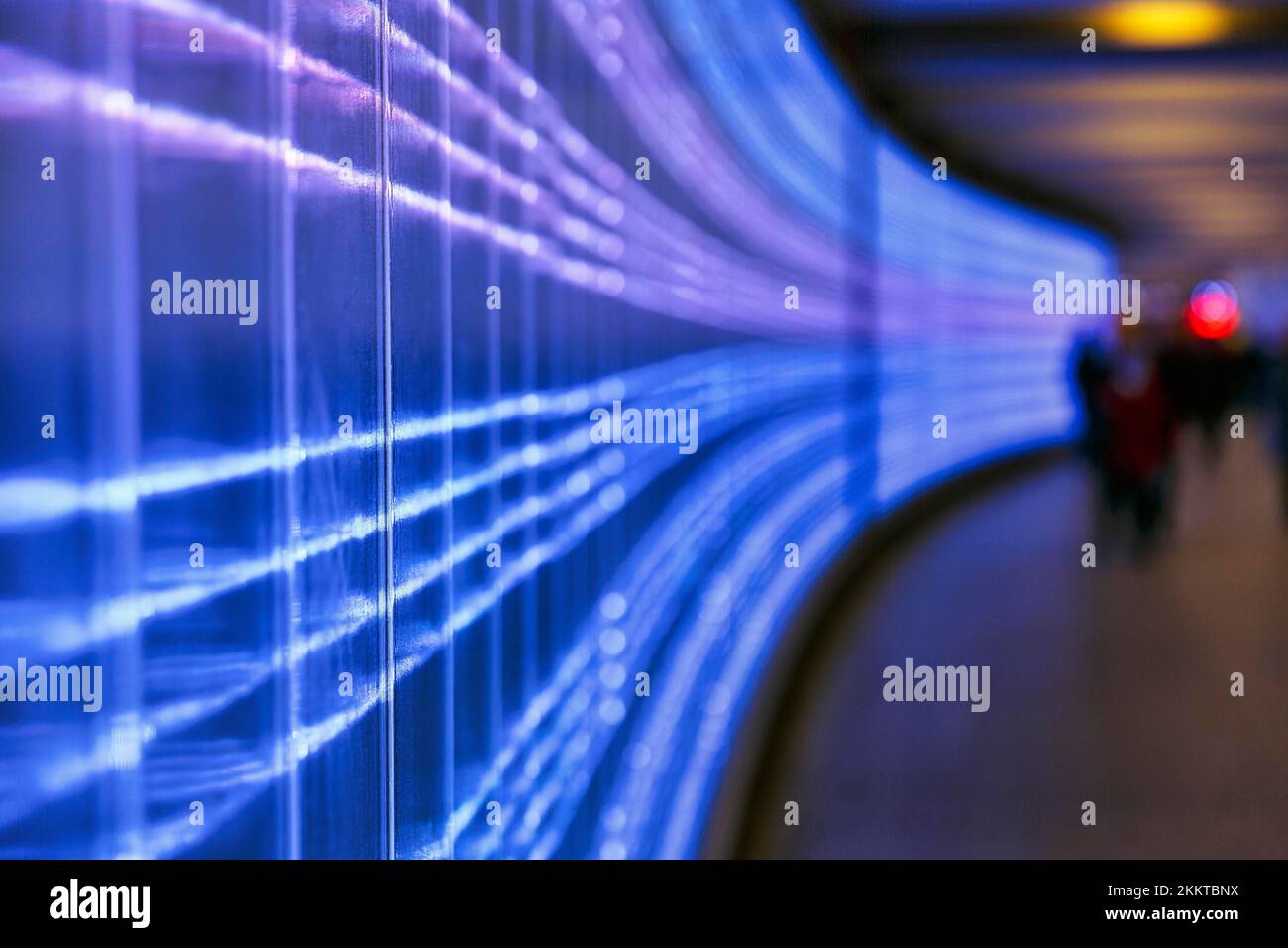 Passers-by in underground passage Passerelle, blue illuminated wall ...