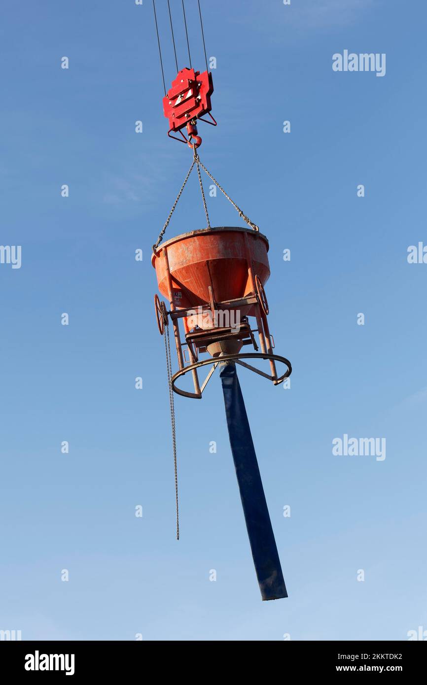 Concrete bucket with hose, hanging from crane, blue sky, large ...