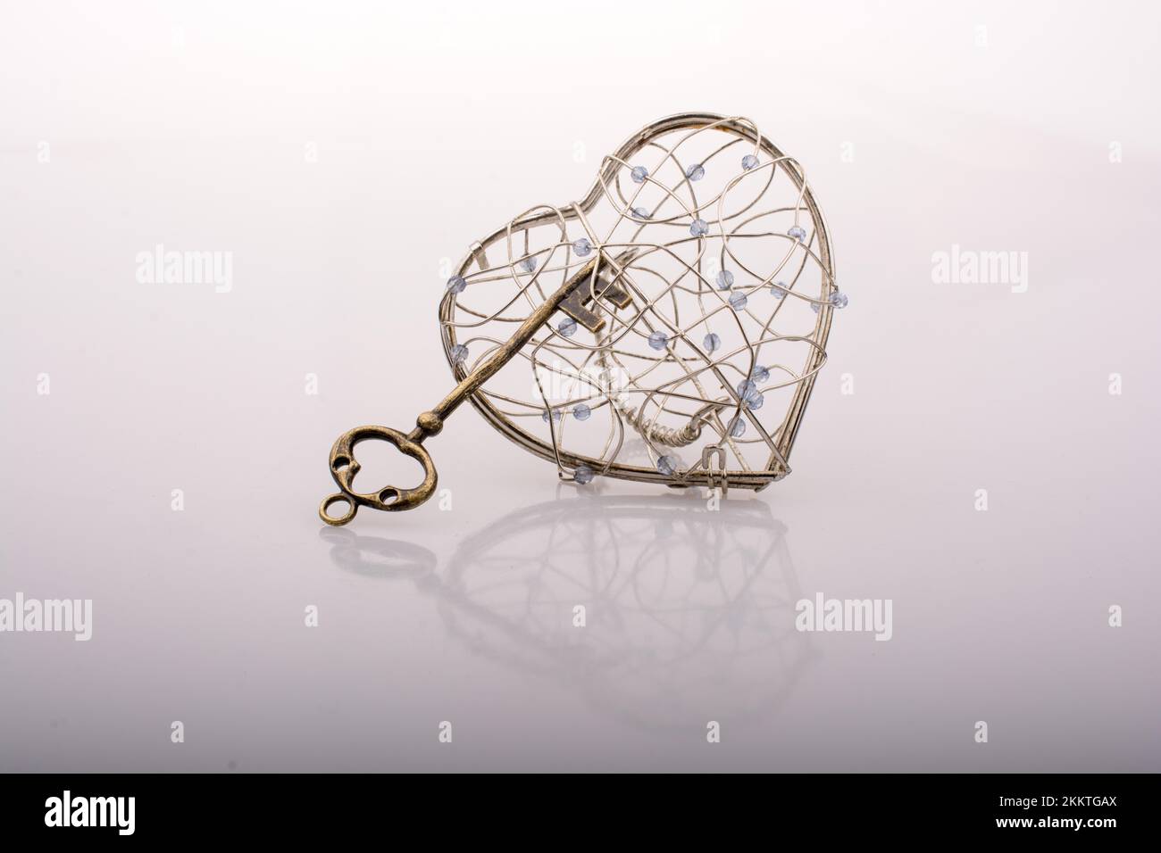 Key and a heart shaped metal cage on white Stock Photo - Alamy