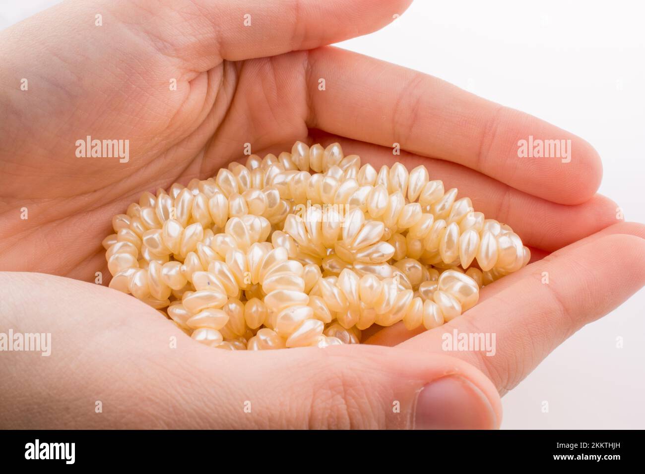 Hand holding pearl necklace on white background Stock Photo - Alamy