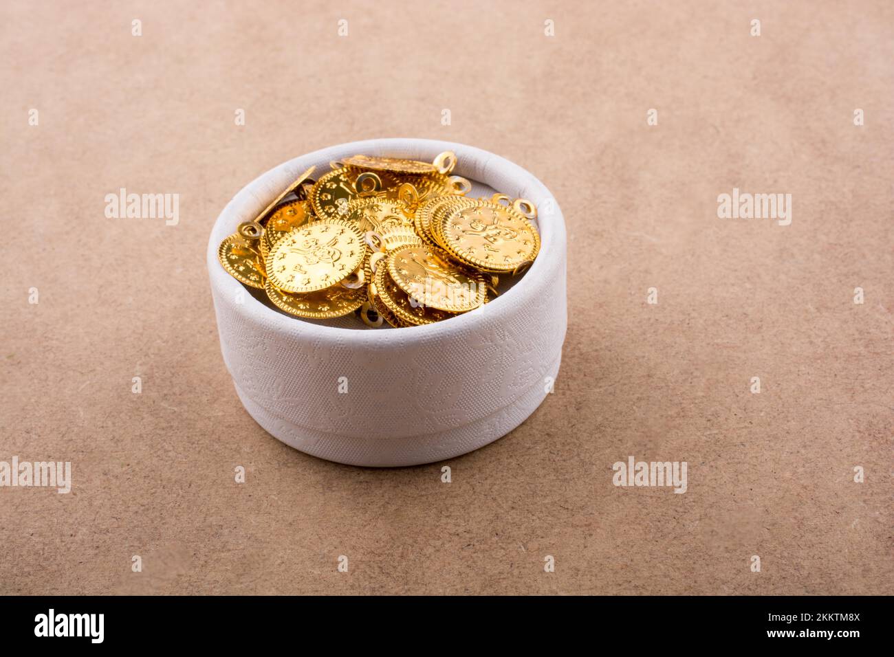 Fake gold coins in white box on brown background Stock Photo - Alamy