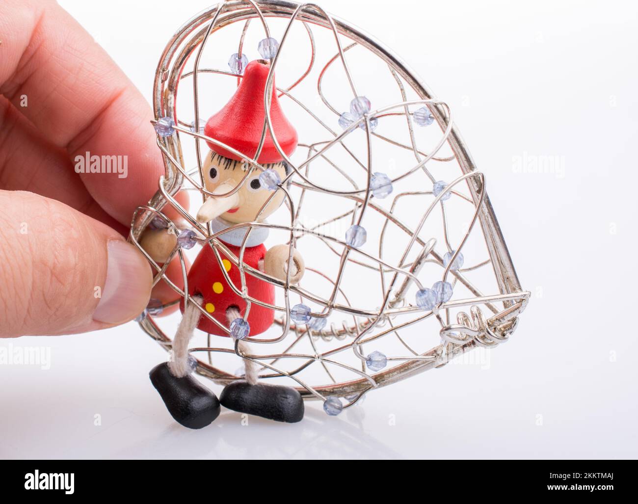 Wooden Pinocchio doll sitting in a heart shaped cage Stock Photo - Alamy