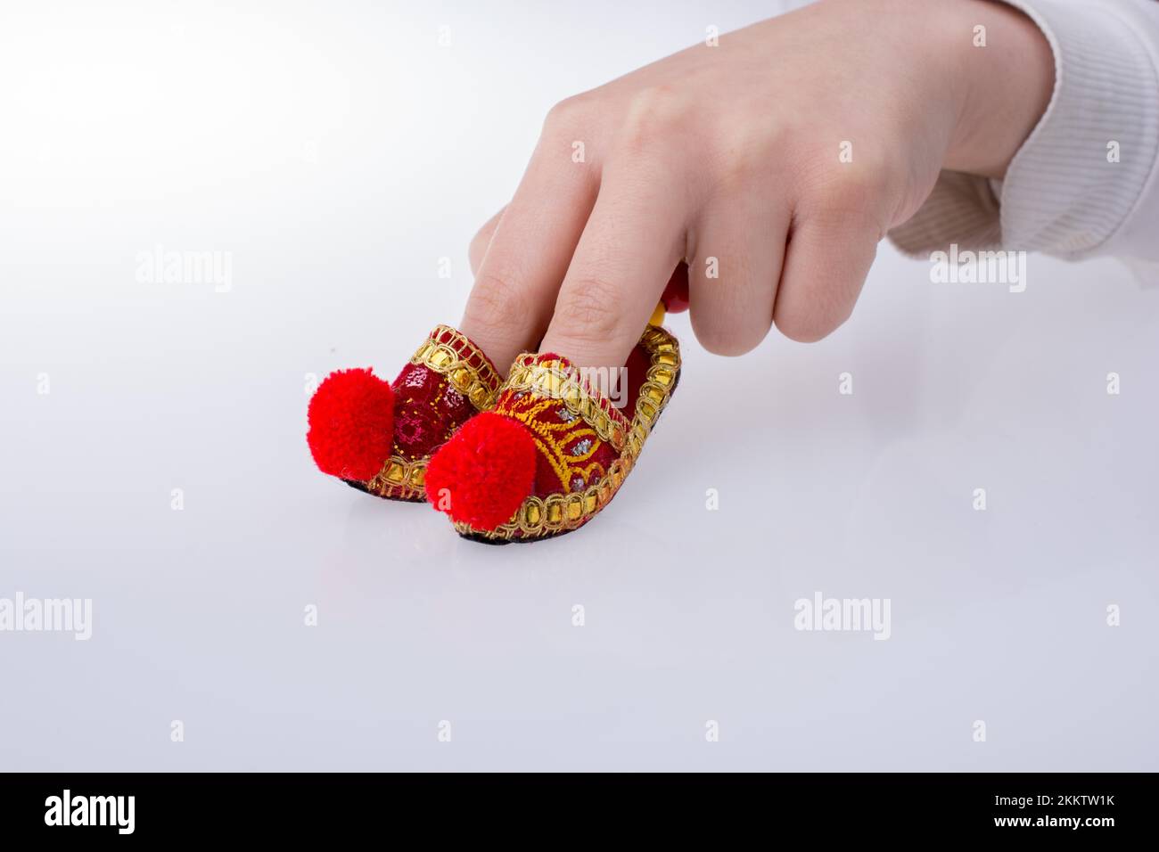 Hand holding traditional Turkish handmade shoes on white background ...