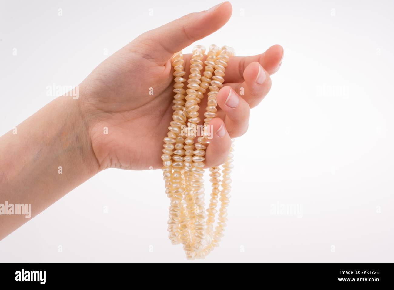 Hand holding pearl necklace on white background Stock Photo - Alamy