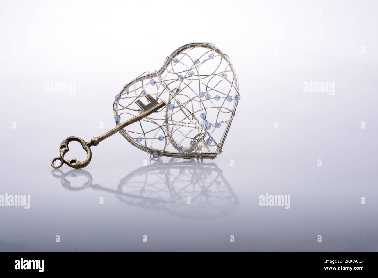 Key and a heart shaped metal cage on white Stock Photo - Alamy