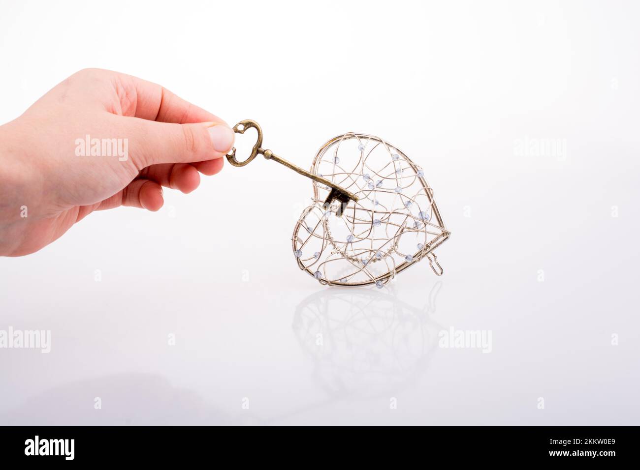 Key and a heart shaped metal cage on white Stock Photo - Alamy