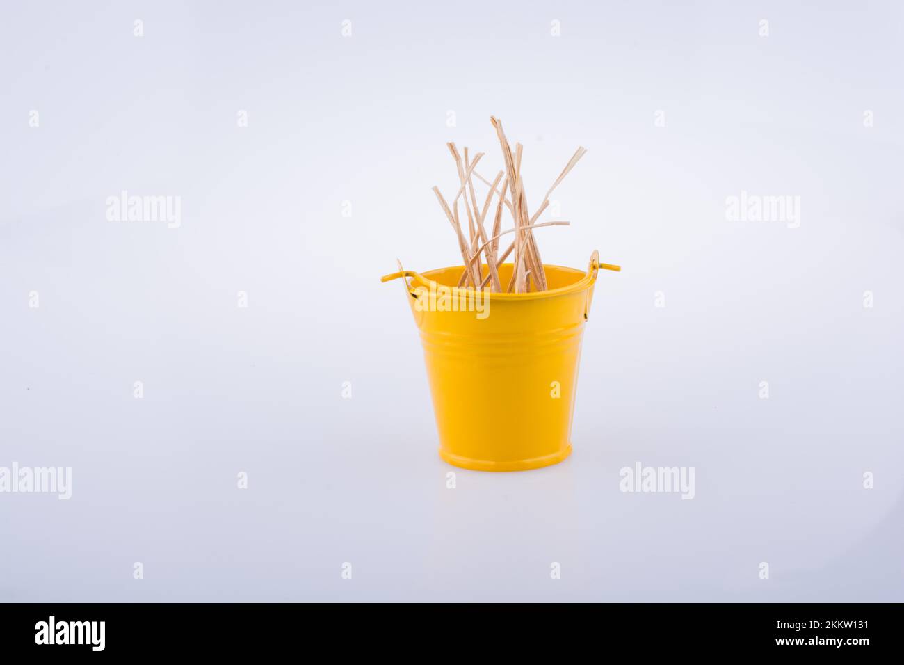 Straw in a yellow color bucket on a white background Stock Photo - Alamy