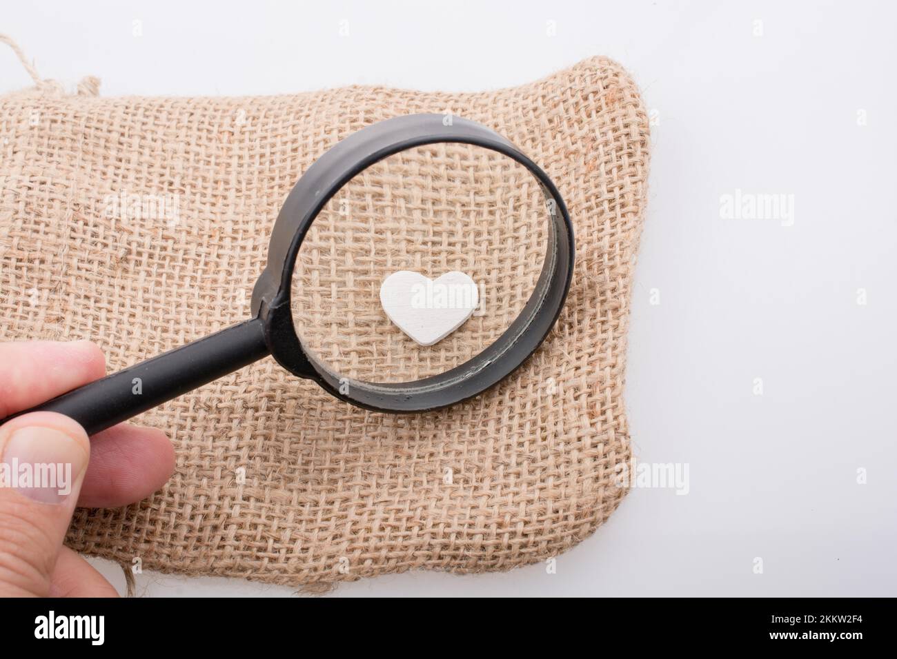 Heart shaped metal object behind magnifying glass Stock Photo - Alamy