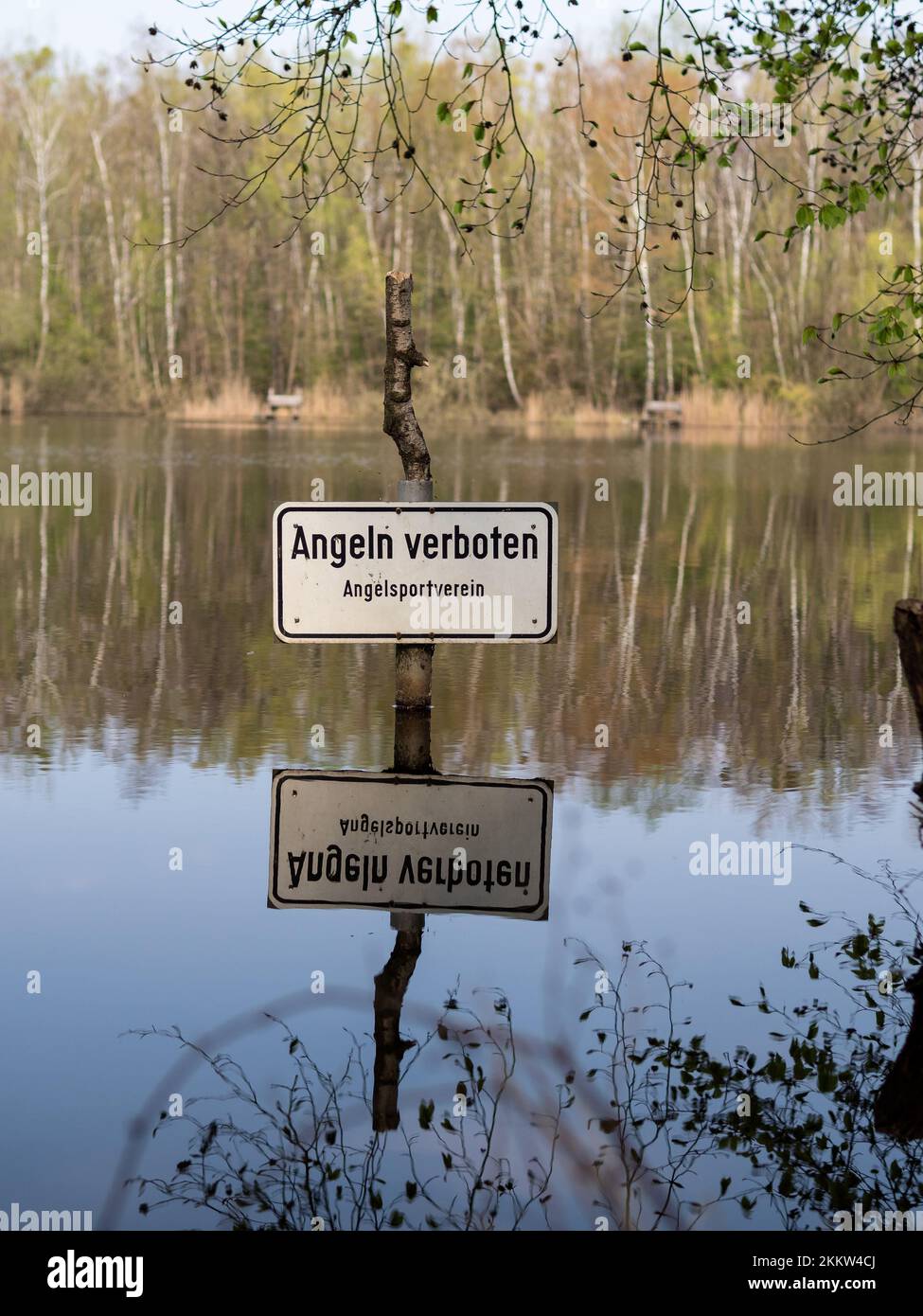 A vertical shot of a sign in German on a wooden stick symmetrically ...