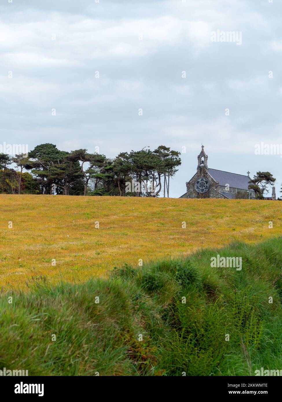 A stone Christian church in the distance of a beautiful meadow. Cloudy ...