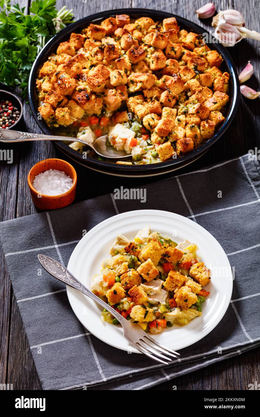 turkey pot pie with stuffing crust in baking dish and on plate on dark ...