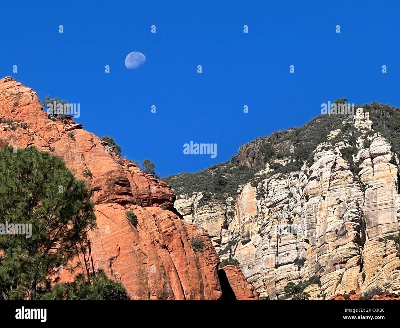 The moon in a blue sky over the mountains of Slide Rock State Park in ...