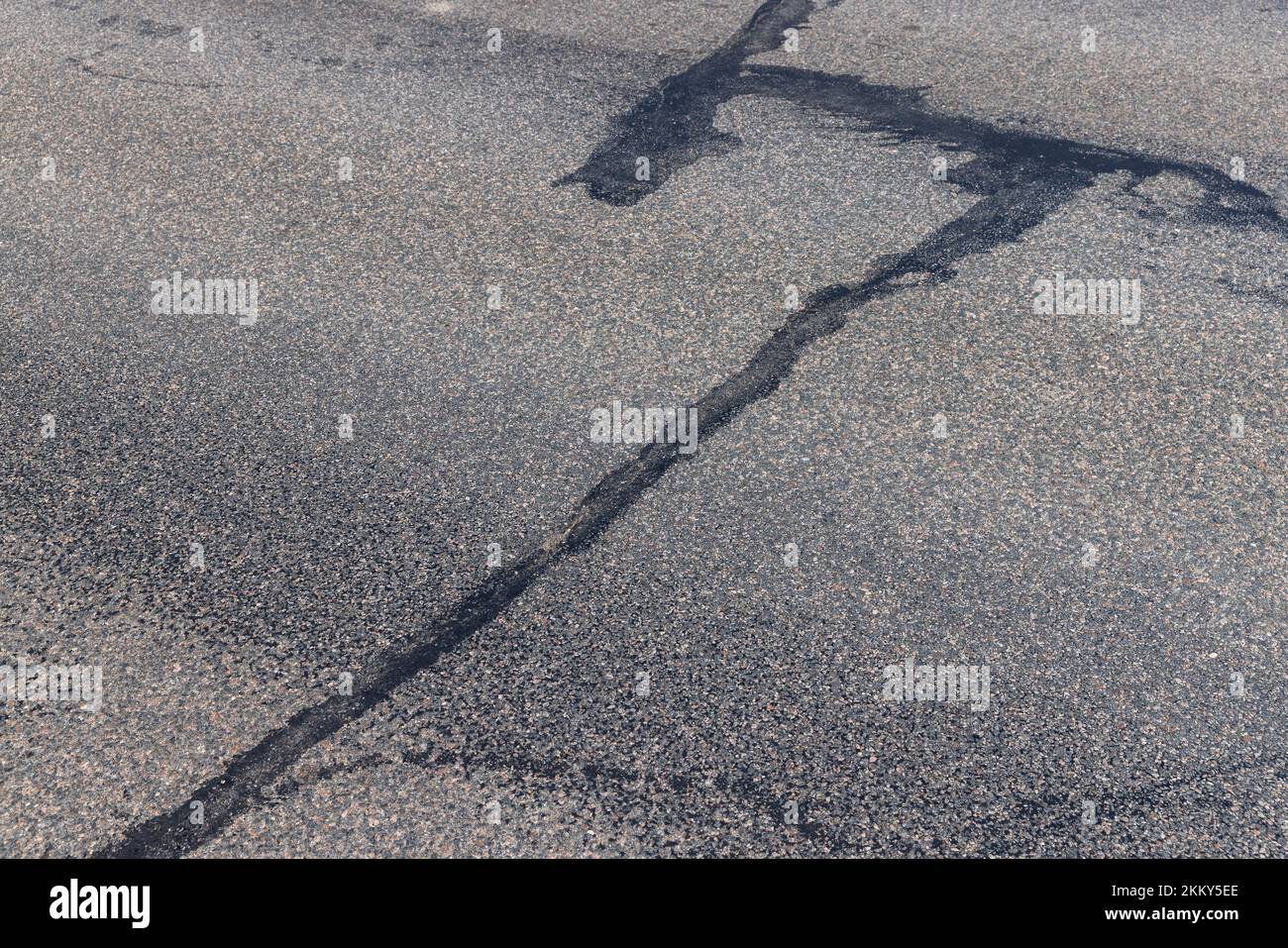 Repaired asphalt road in close up, paved road with traces of repair and ...