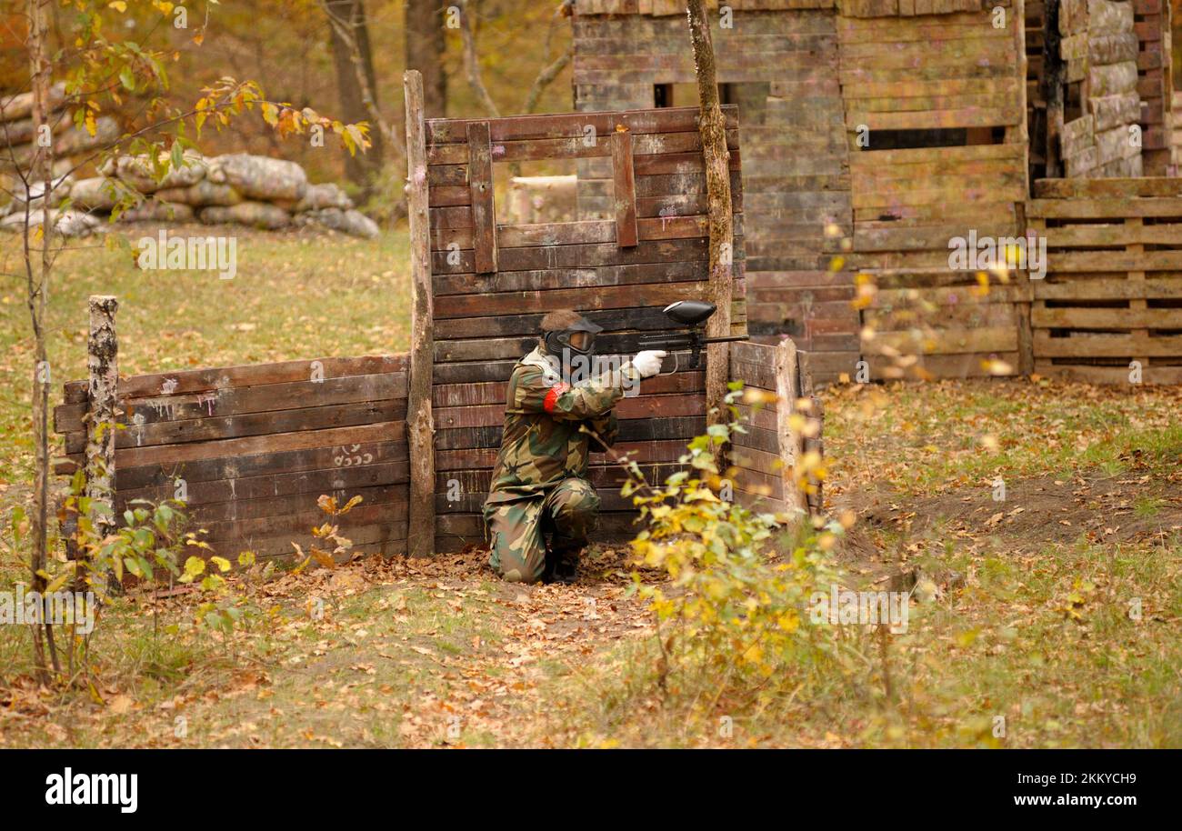 Man player shooting with a paintball gun hiding behind wooden shelter ...