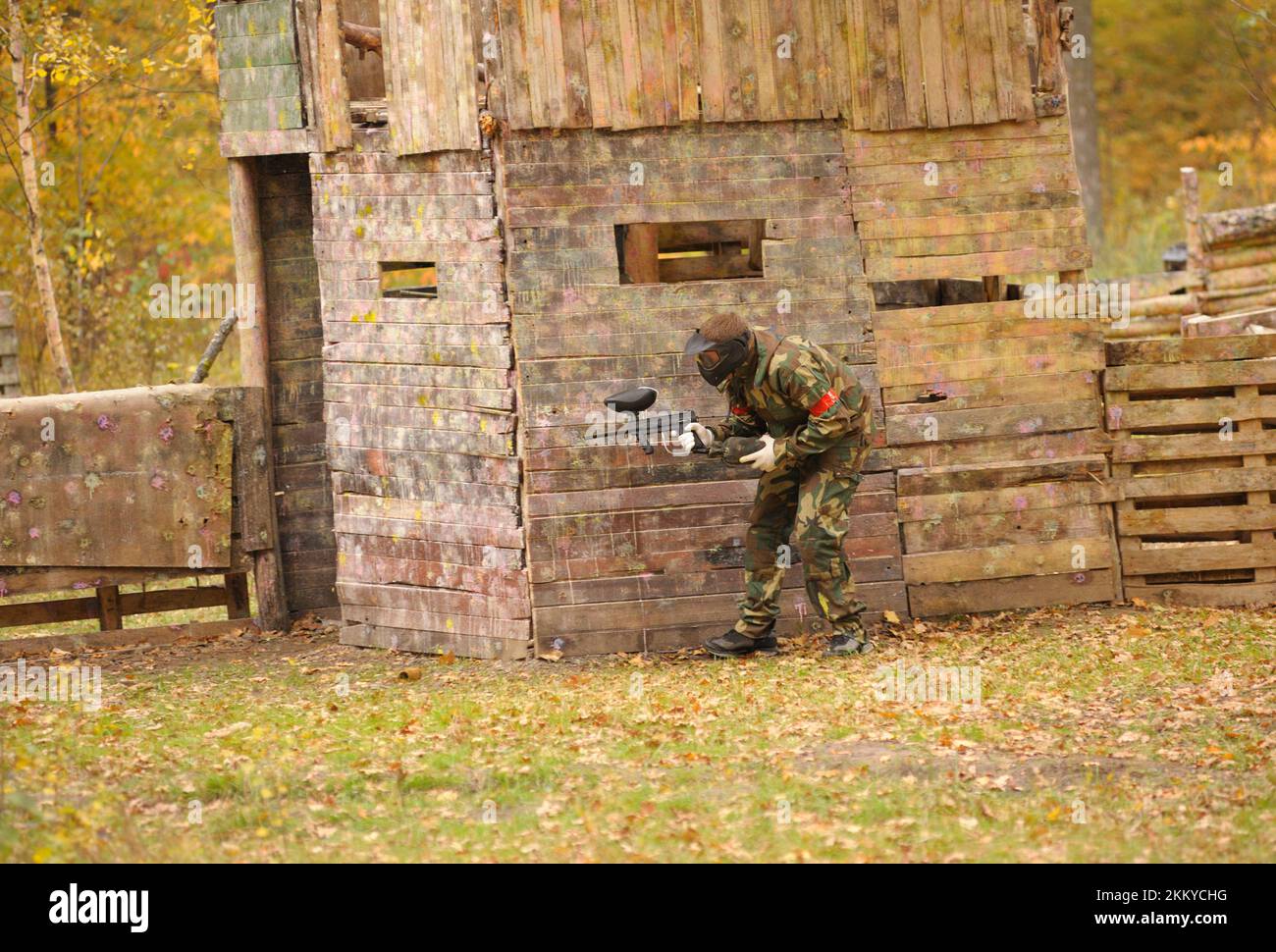 Man player shooting with a paintball gun hiding behind wooden shelter ...