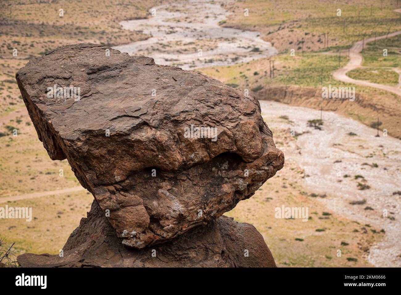 A closeup of a stack of huge rocks surrounded by a green landscape ...