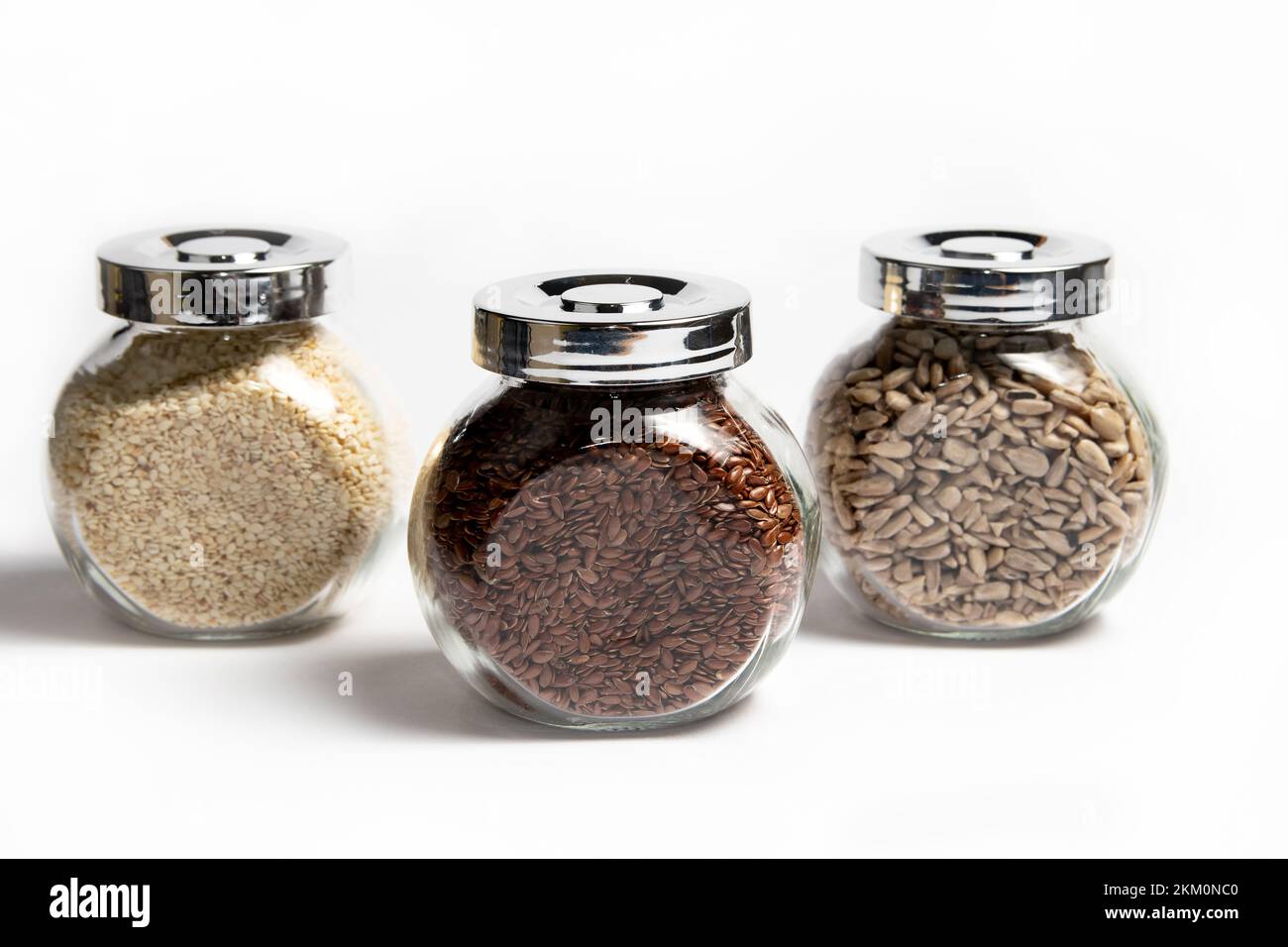 Glass jars with sesame seeds flax seeds sunflower seeds on white ...
