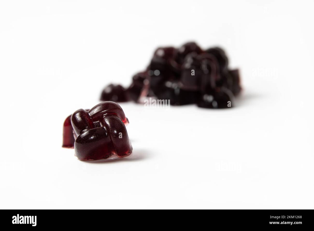 Dark red cherry homemade gelatin candy on white background with a heap ...