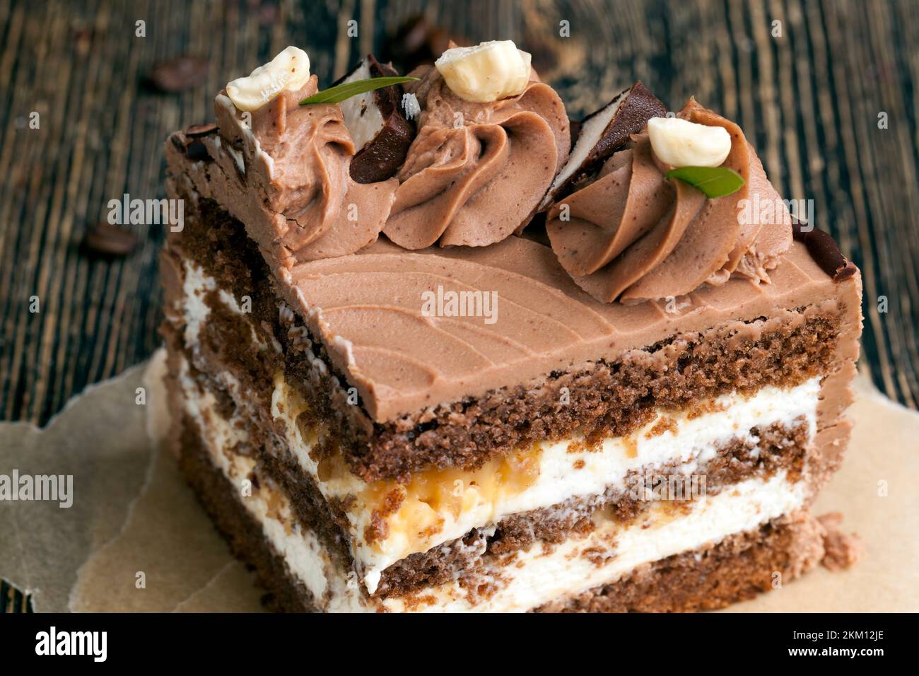 layered cake with chocolate cakes, caramel cream and hazelnuts, a piece ...