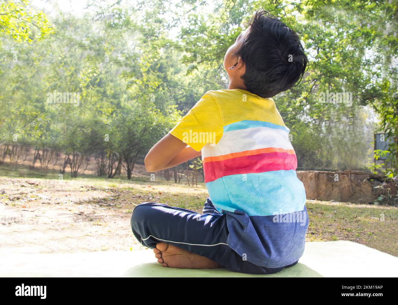 back view Young Boy doing yoga with hands in prayer position at outdoor ...