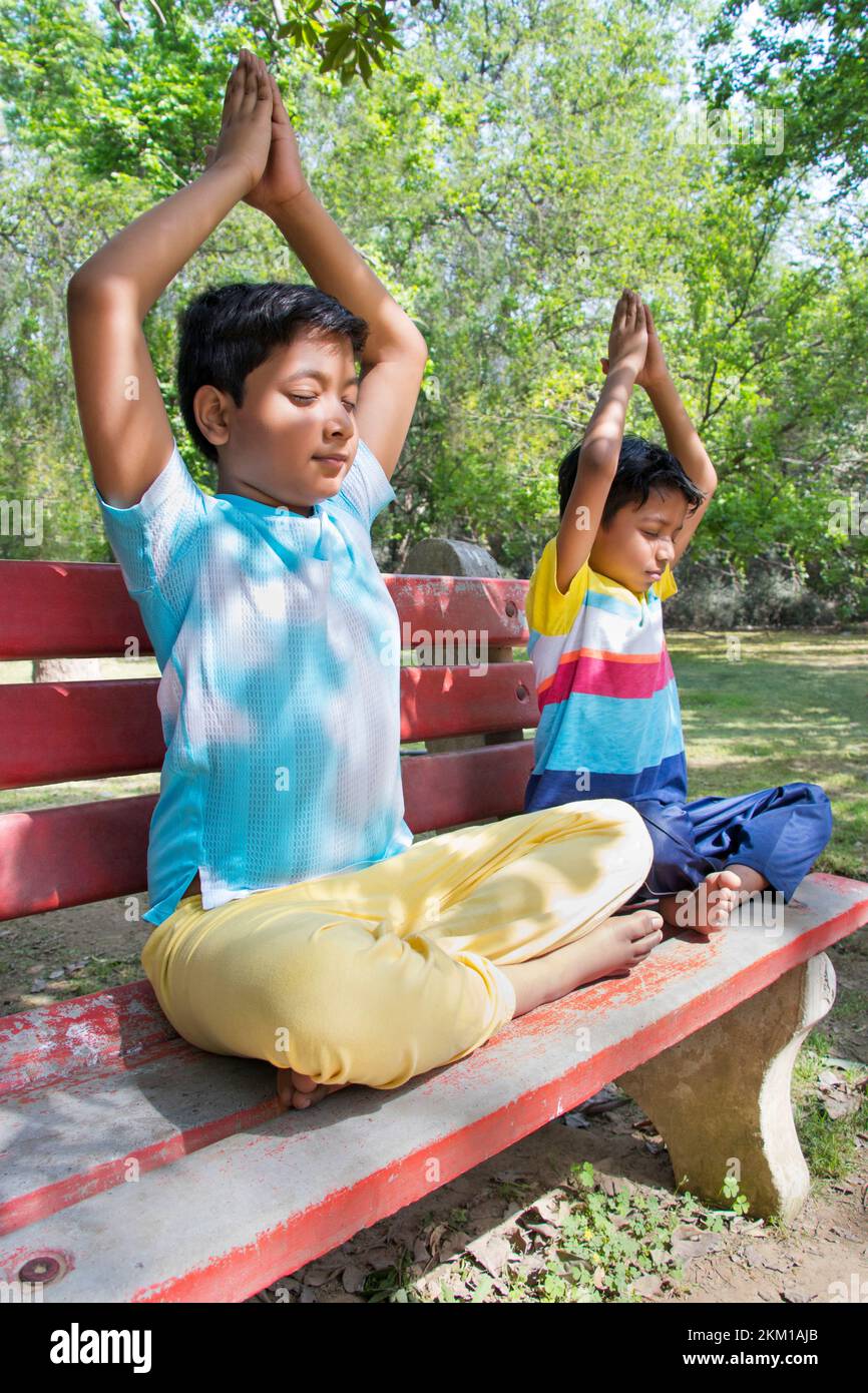 Two boys meditating in prayer position at park Stock Photo - Alamy