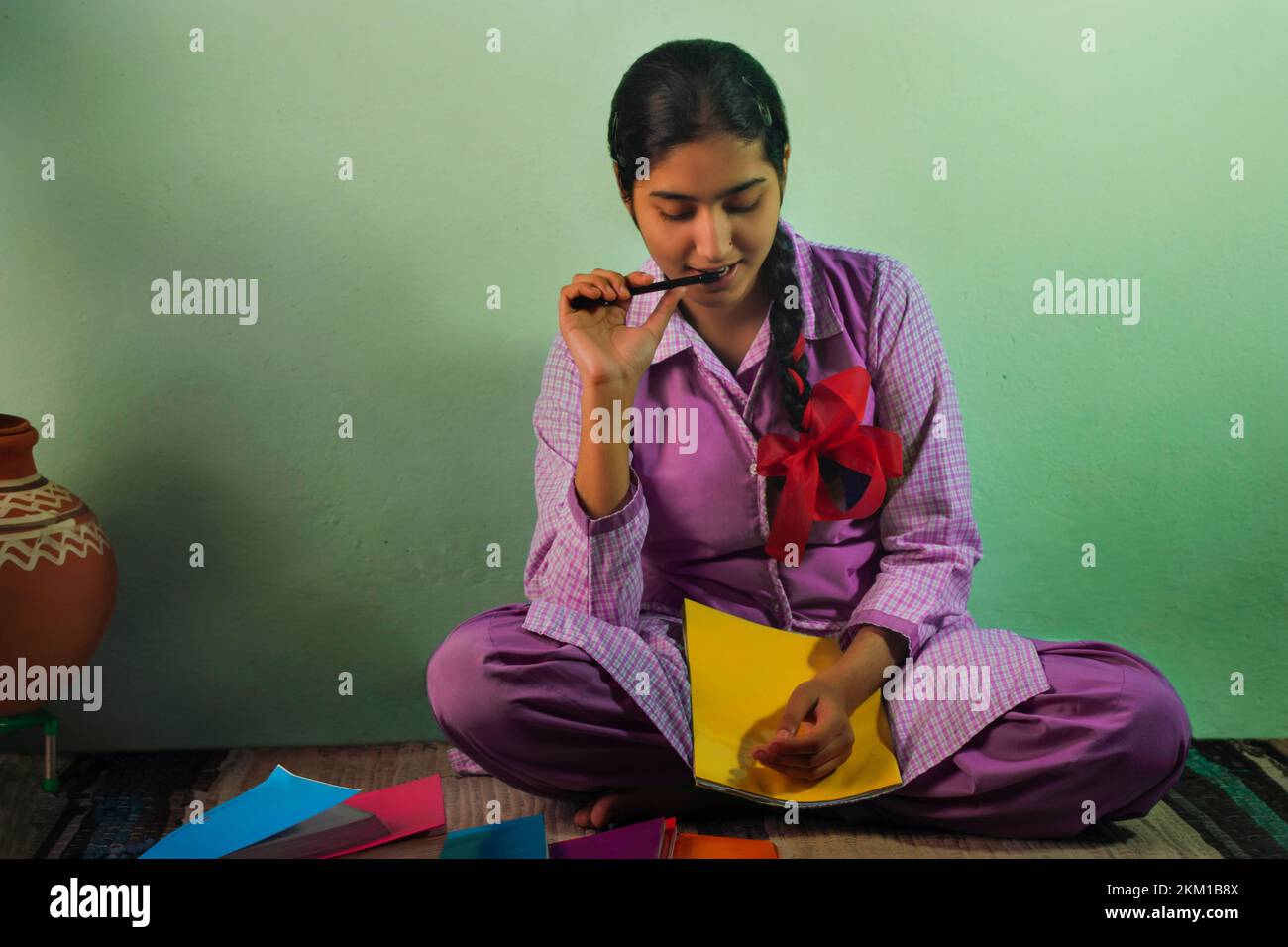 A girl in school uniform thinking while studying at home Stock Photo ...