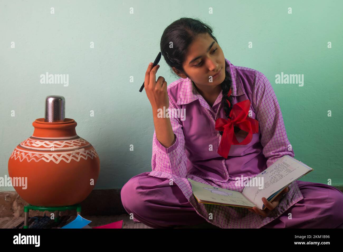 A girl in school uniform thinking while studying at home Stock Photo ...