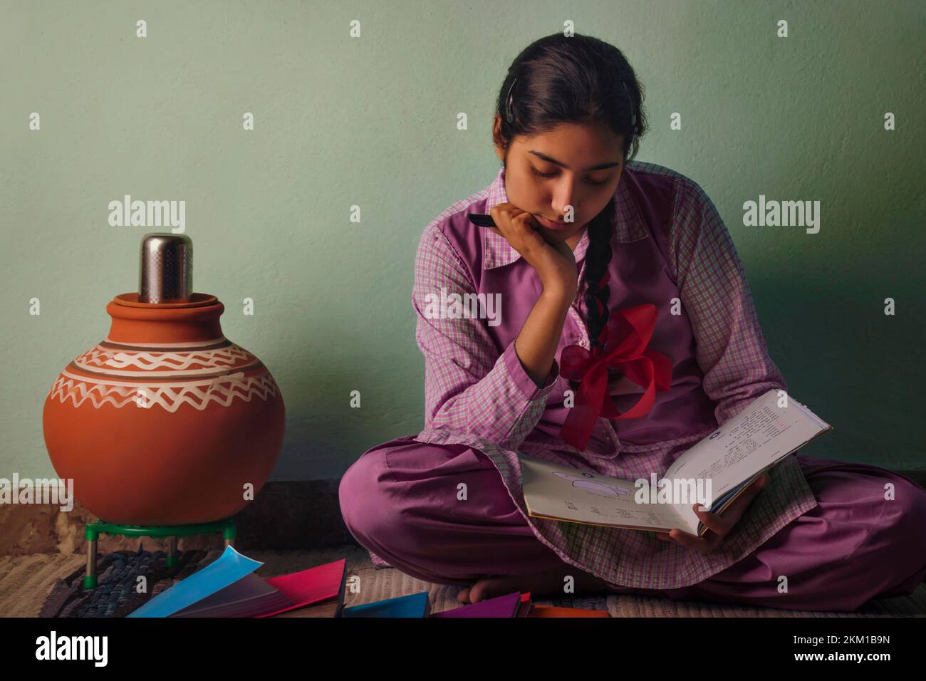 A girl in school uniform thinking while studying at home Stock Photo ...