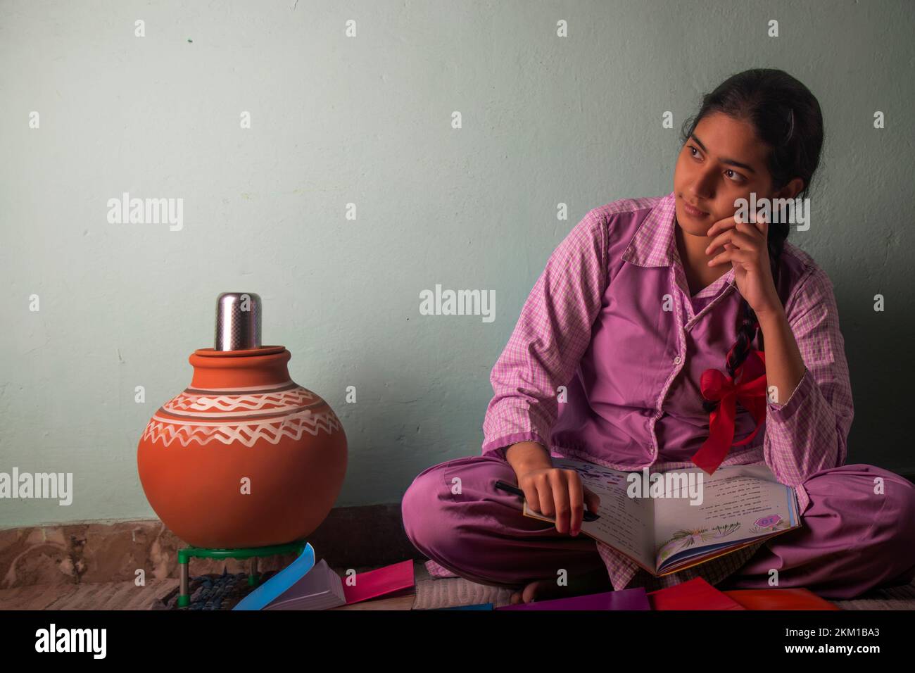 A girl in school uniform thinking while studying at home Stock Photo ...